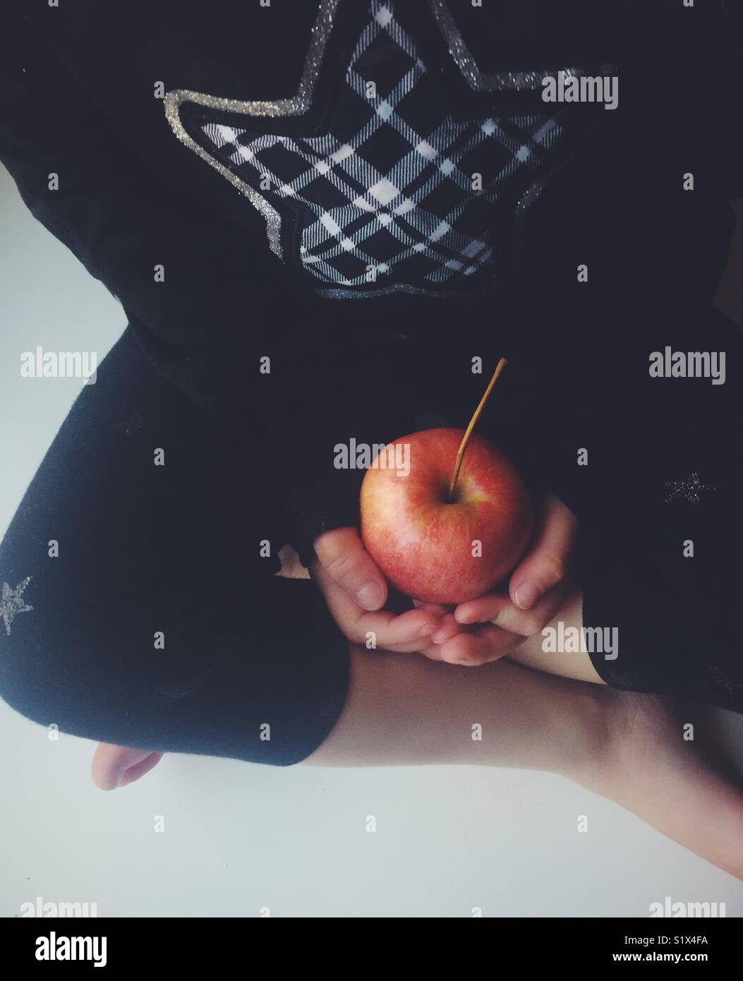 Child holding an apple in their lap Stock Photo - Alamy