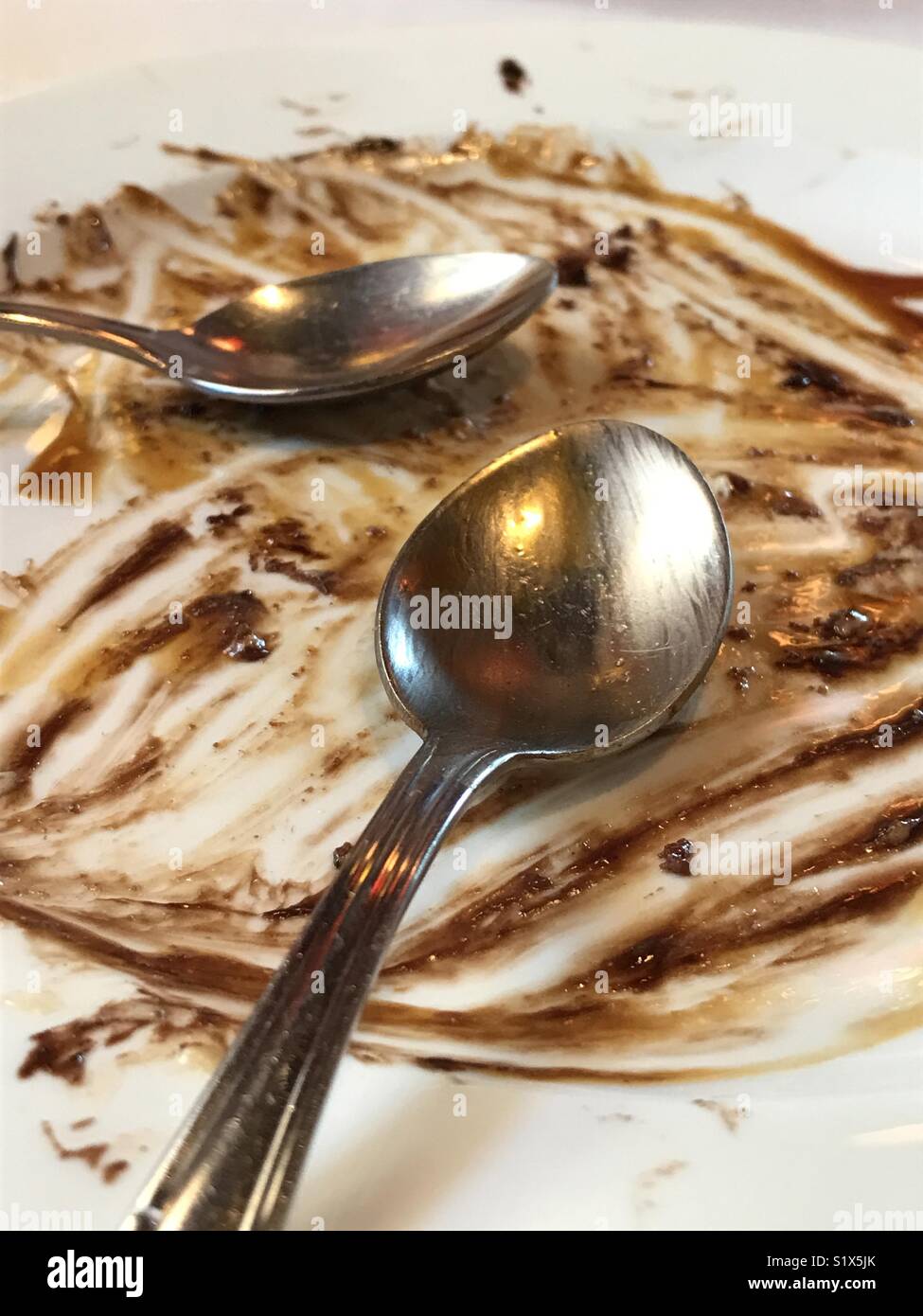 Two spoons on empty dessert dish Stock Photo - Alamy