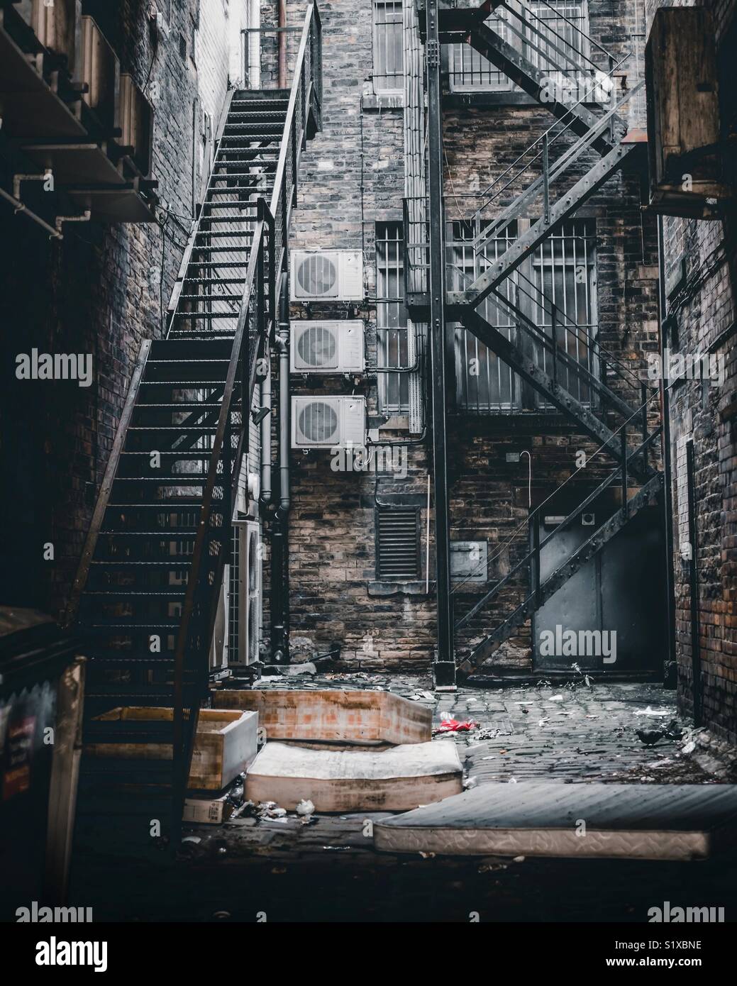 Back alley with fire escape and old mattresses Stock Photo - Alamy