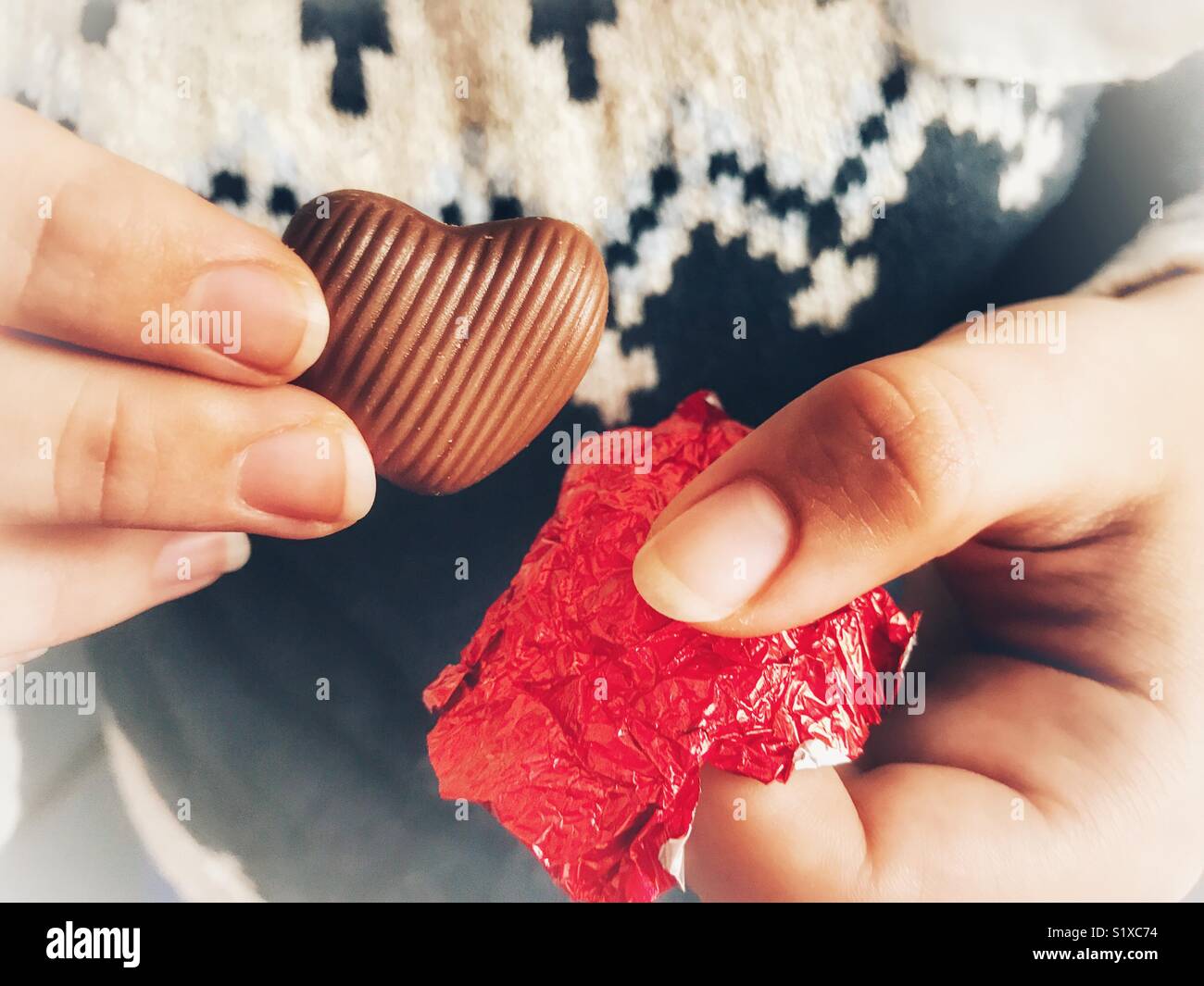 Woman eating a heart shaped, foil wrapped, chocolate heart on Valentine ...