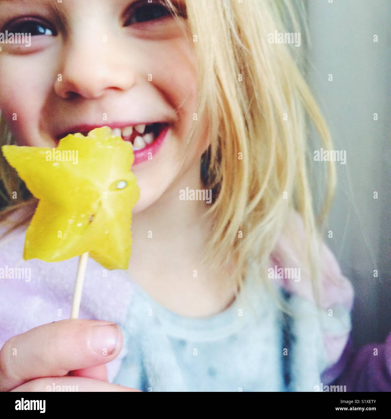 Young girl smiling and eating star fruit Stock Photo - Alamy