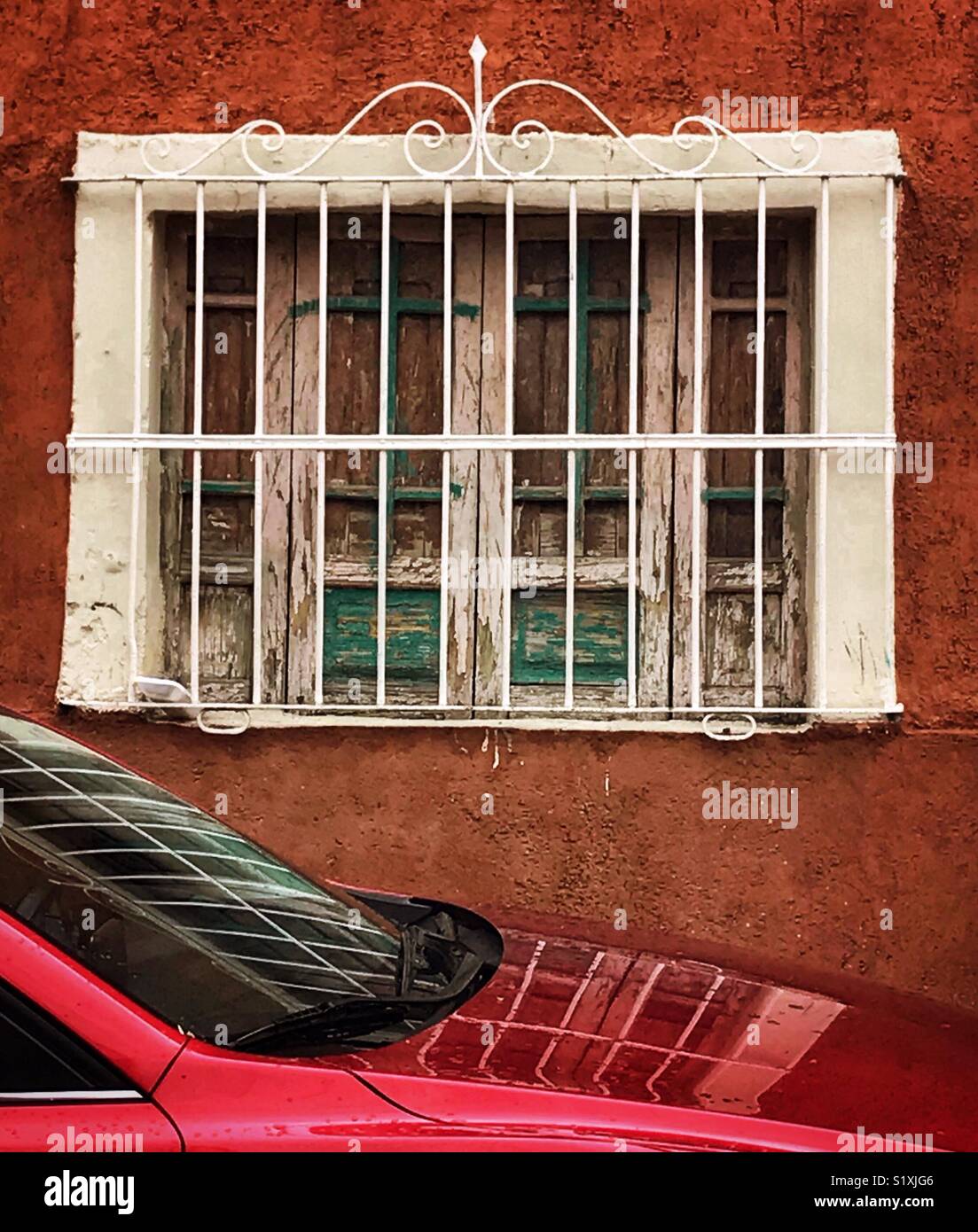 A shuttered window with rich textures is reflected on the window and ...