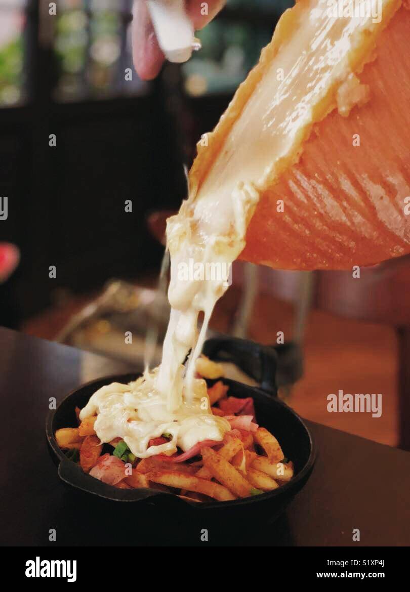 Melted Raclette cheese being poured on poutine Stock Photo - Alamy