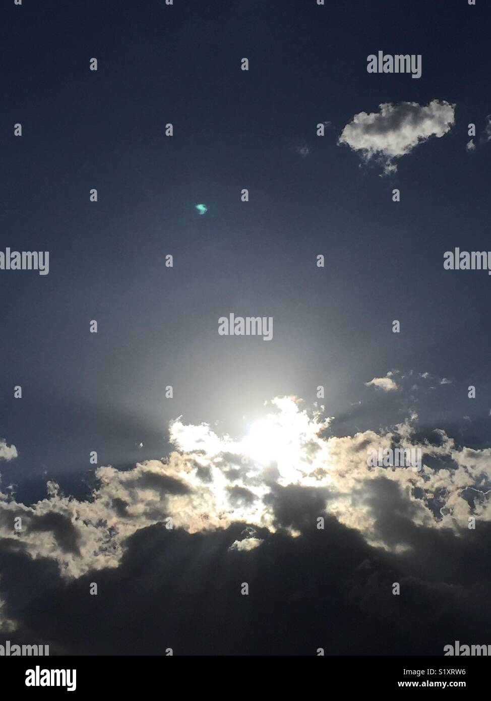 Sun shining through clouds Stock Photo - Alamy