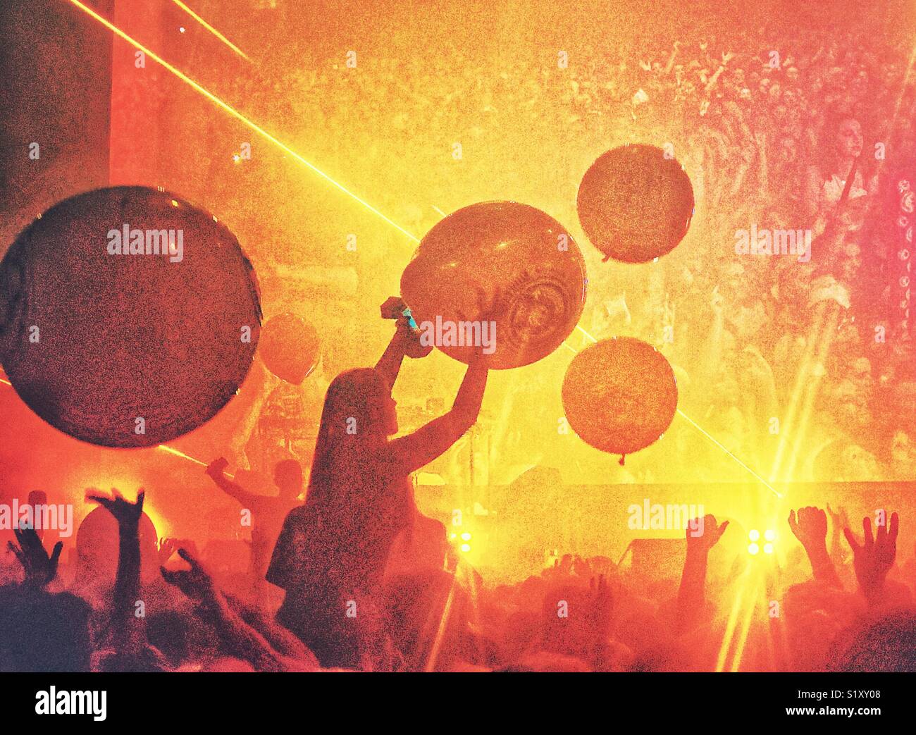 A girl in a huge crowd catching a balloon Stock Photo - Alamy