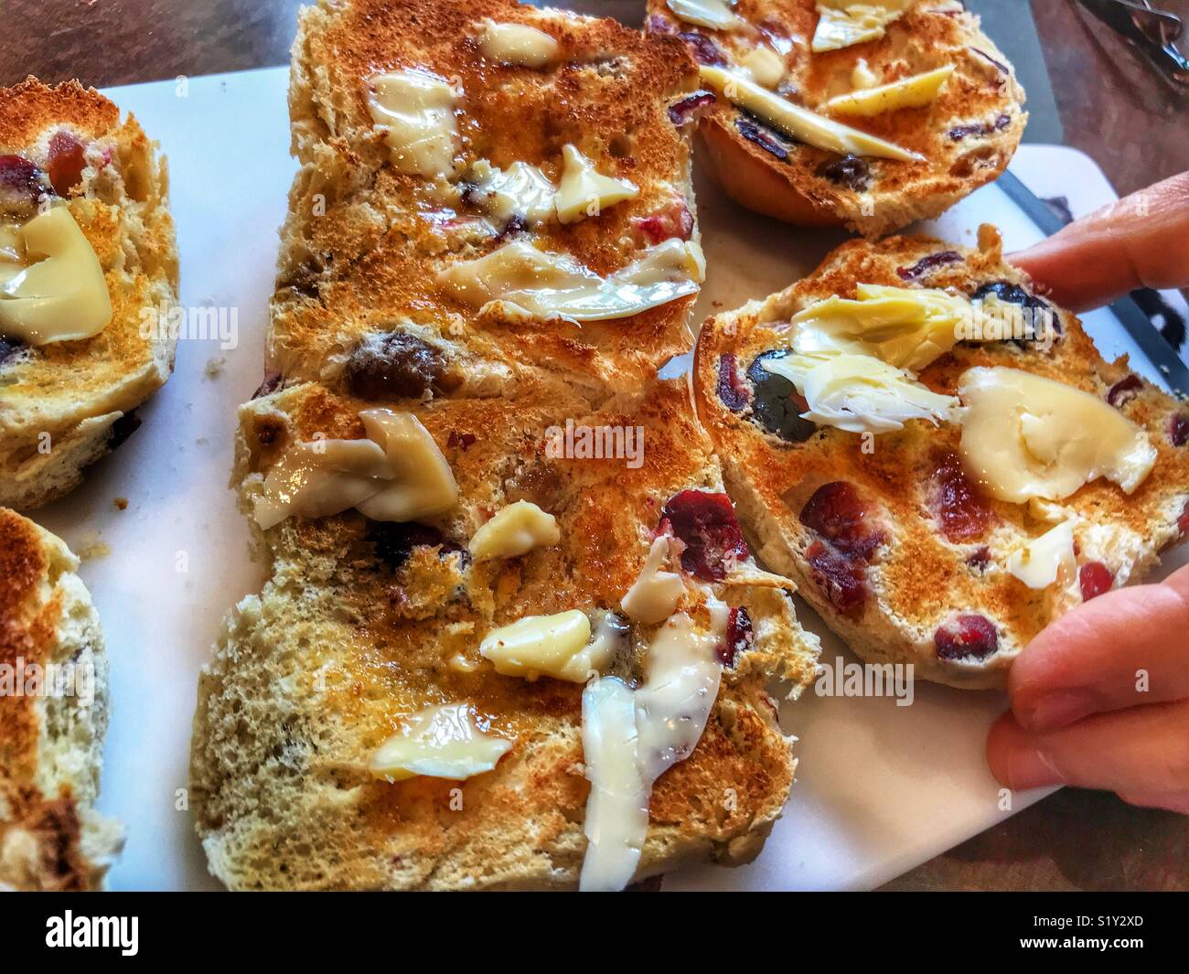 Hand reaching for Hot cross buns, toasted, with plenty of butter Stock ...