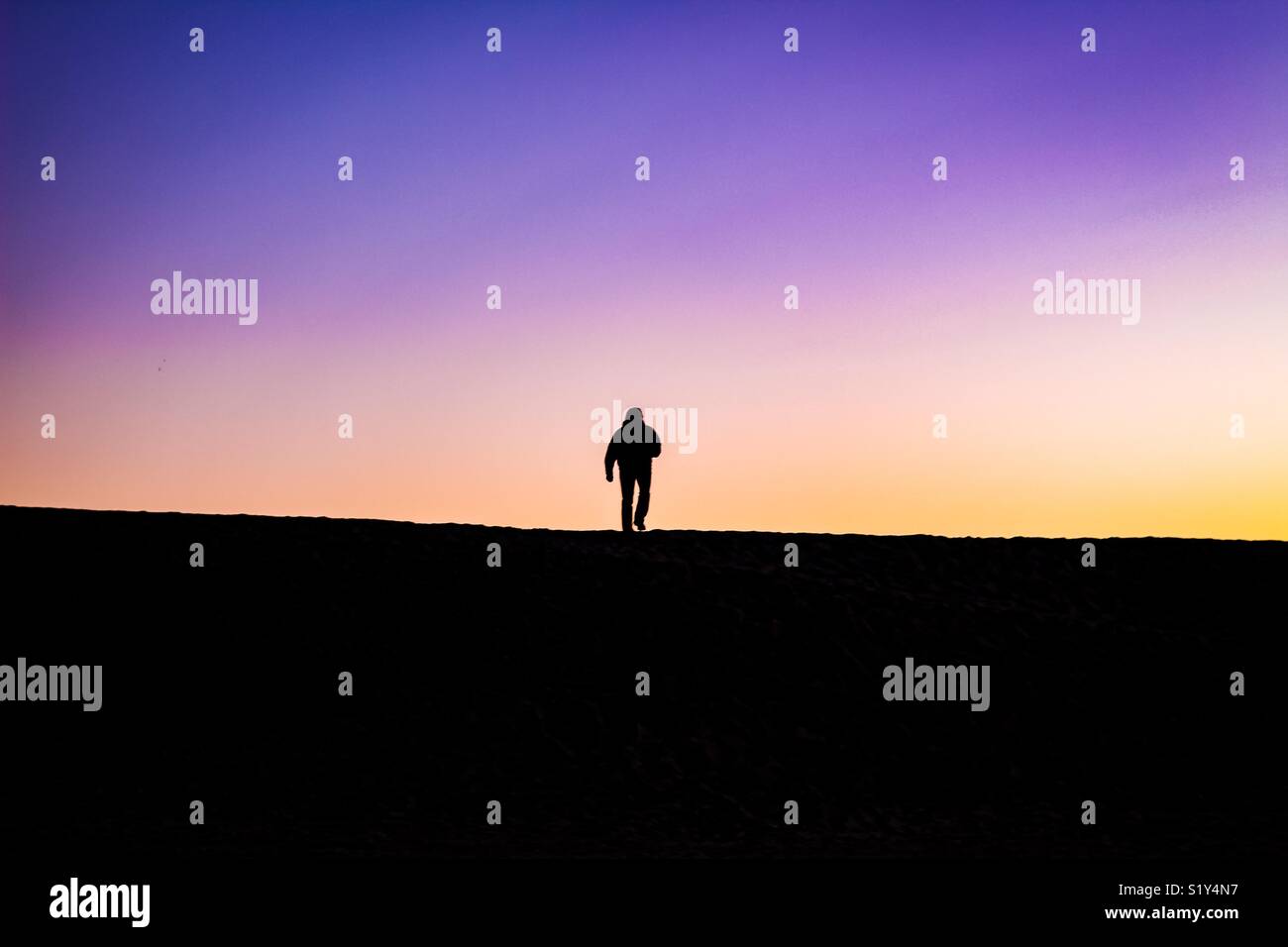 A man walking by him self into a sunset Stock Photo - Alamy