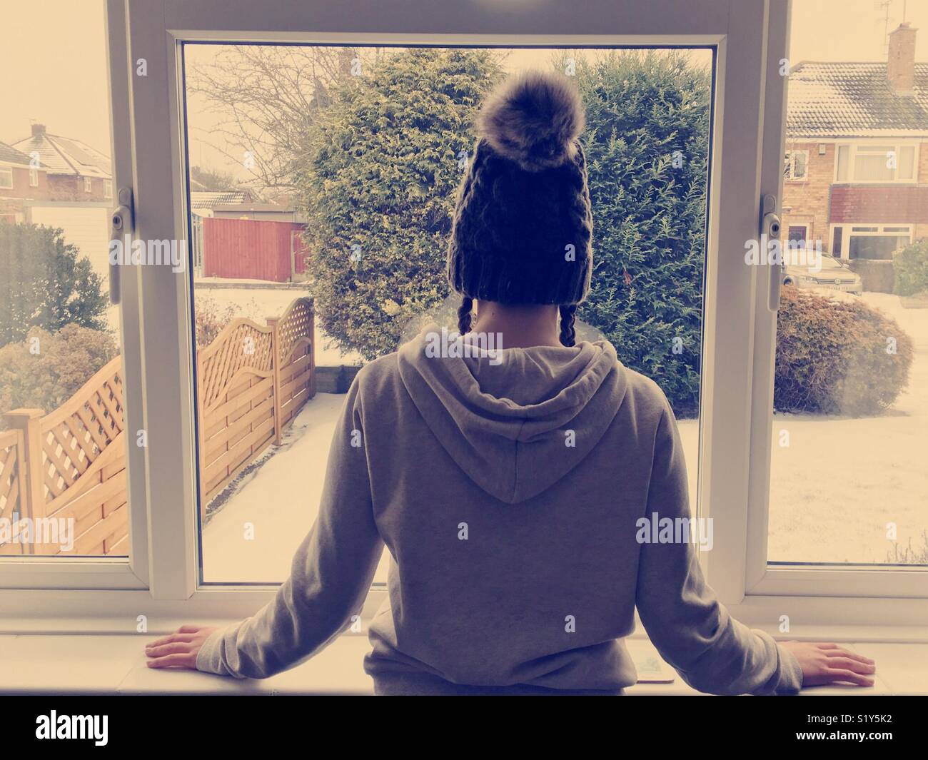 Girl looking out at the snow Stock Photo - Alamy