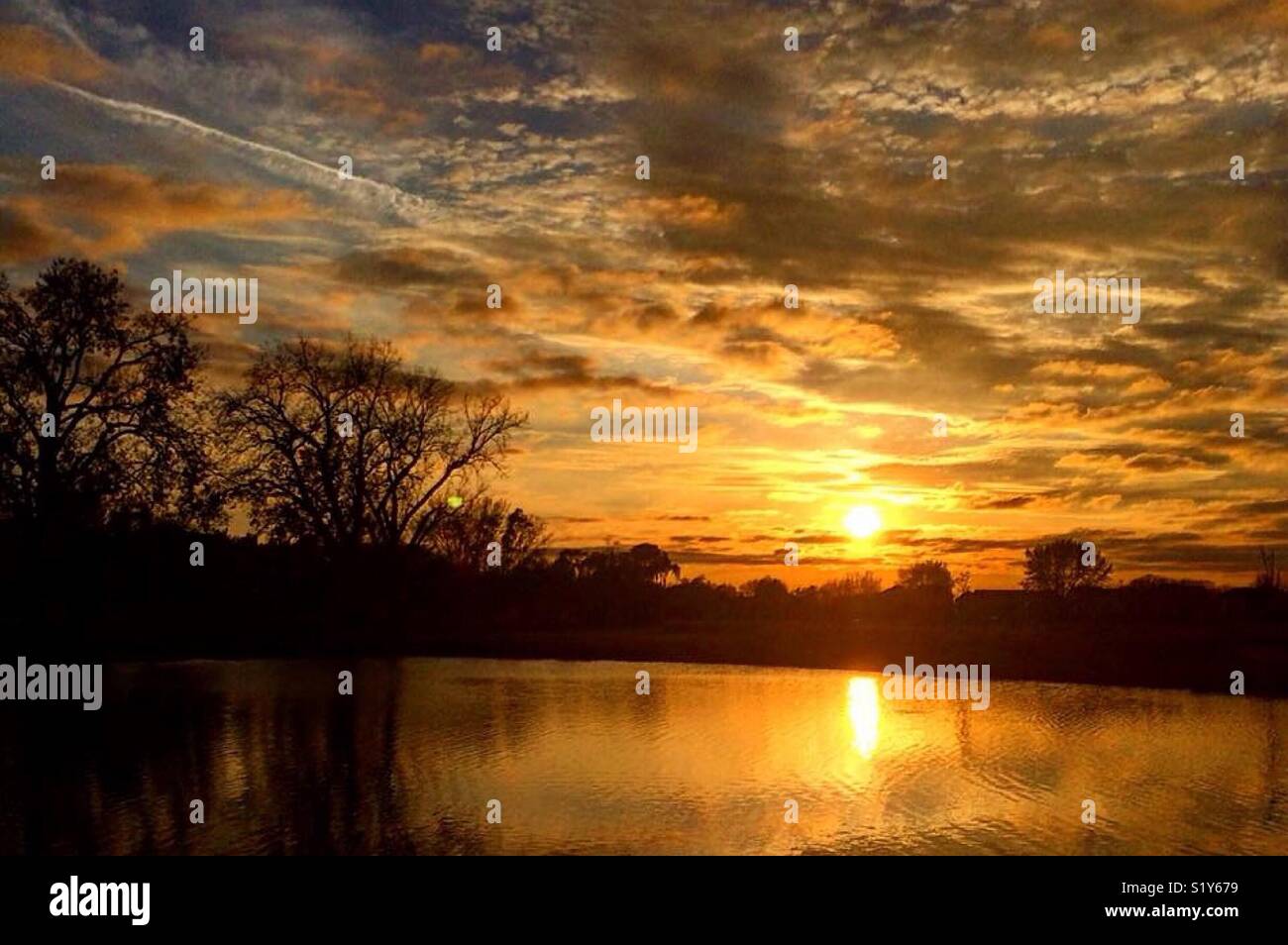 Beautiful golden sunset over a small lake that reflects the color on ...