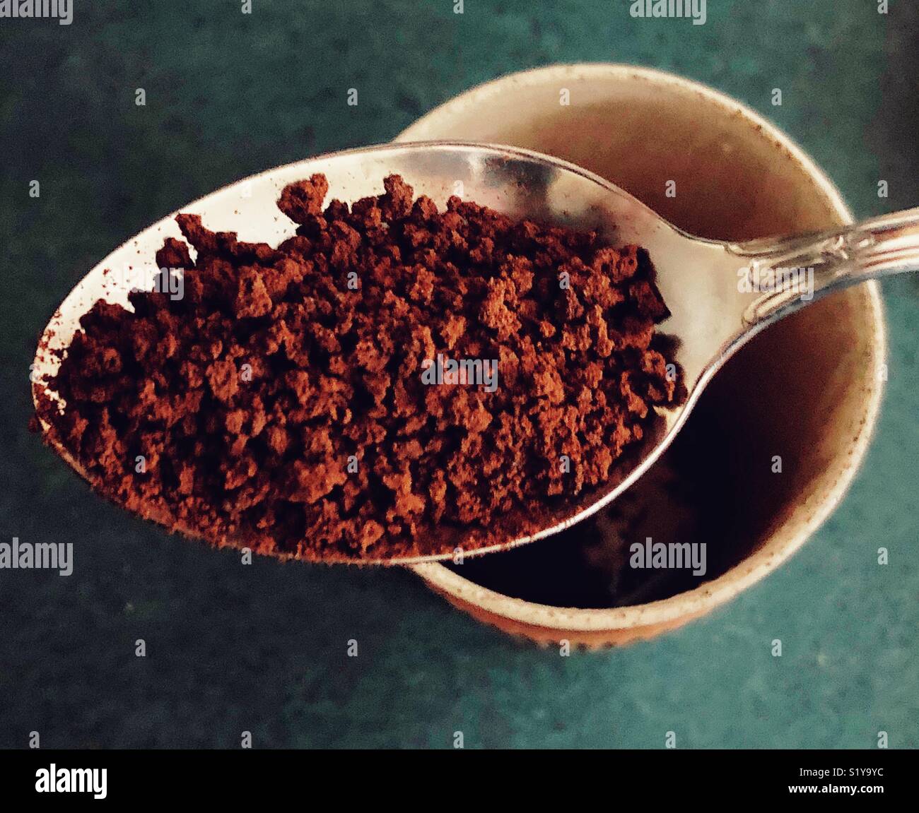 Closeup of instant coffee crystals on a stainless steel spoon above a ...