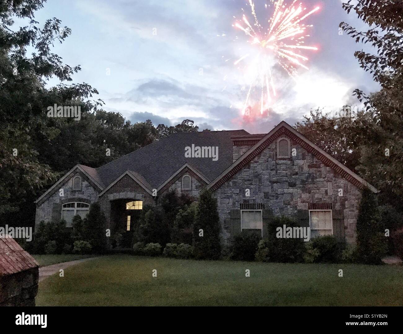 Fireworks go off over a residential home on the Fourth of July Stock ...