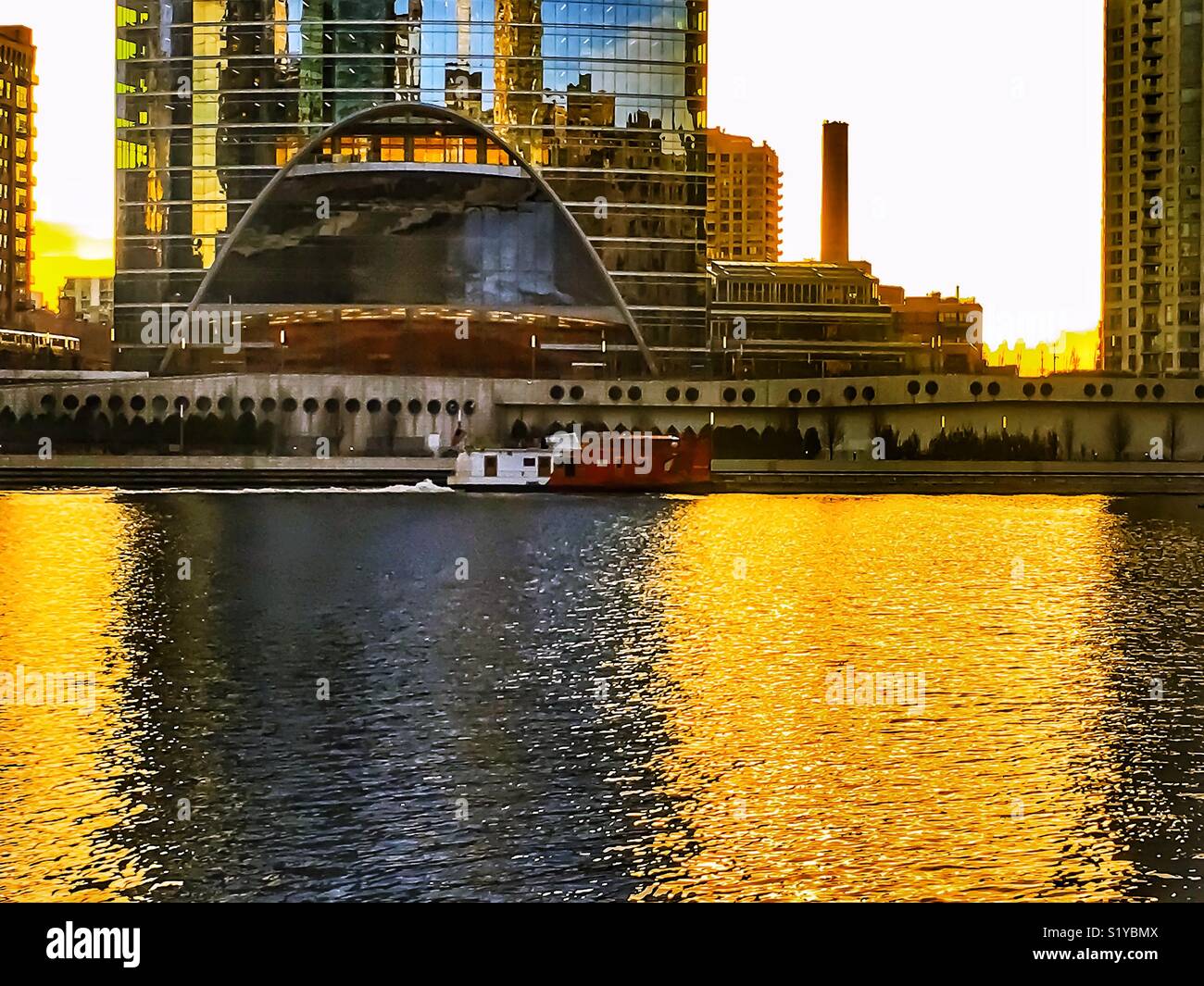 Golden colors surround a tugboat crossing the Chicago River at sunset ...