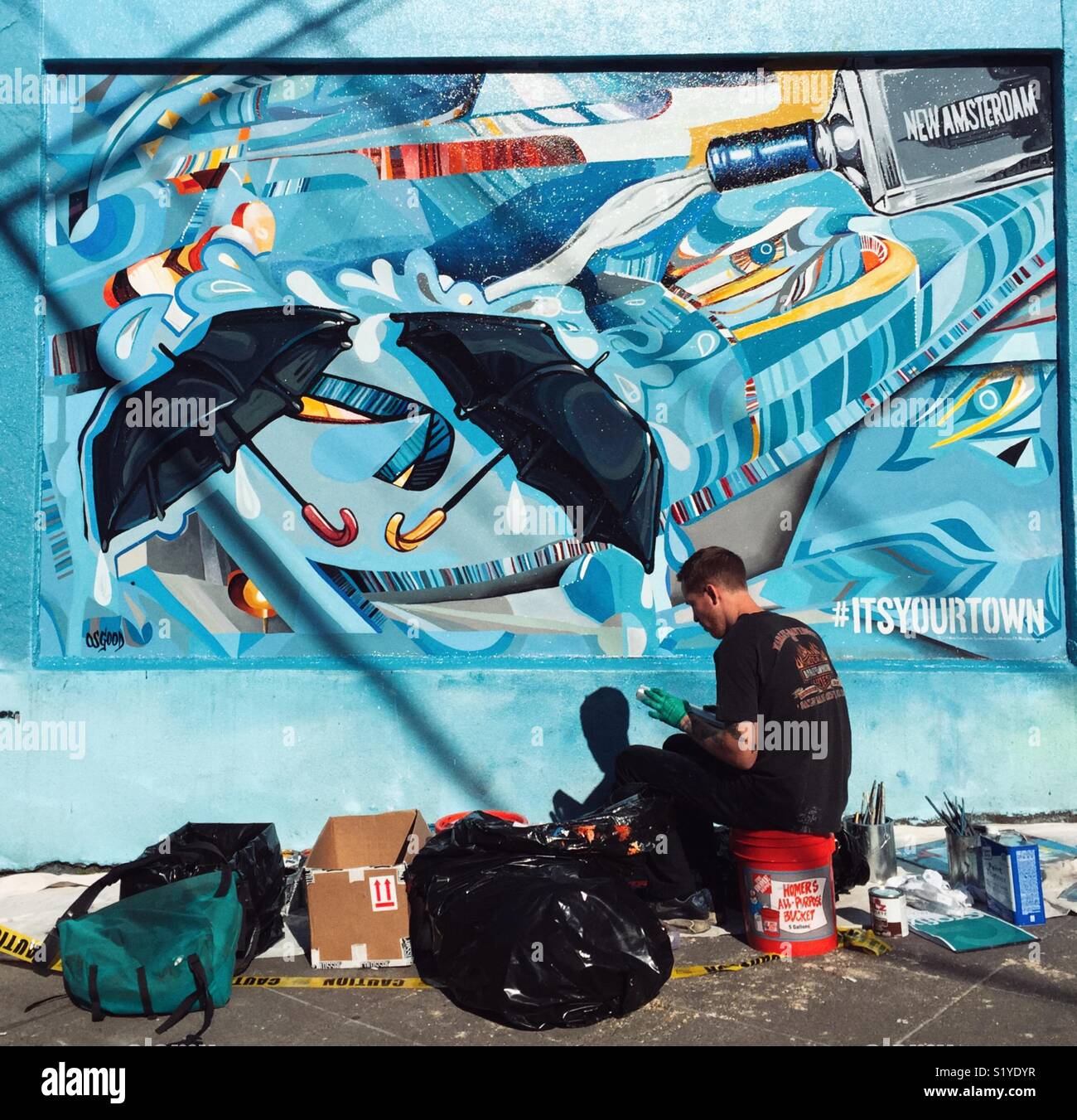 Artist sits in front unfinished mural on the wall of the building in ...
