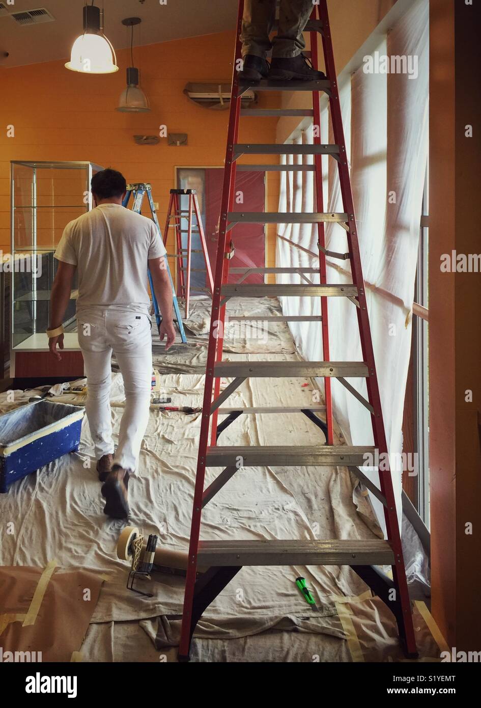 Painter in white clothes walks by ladders Stock Photo - Alamy