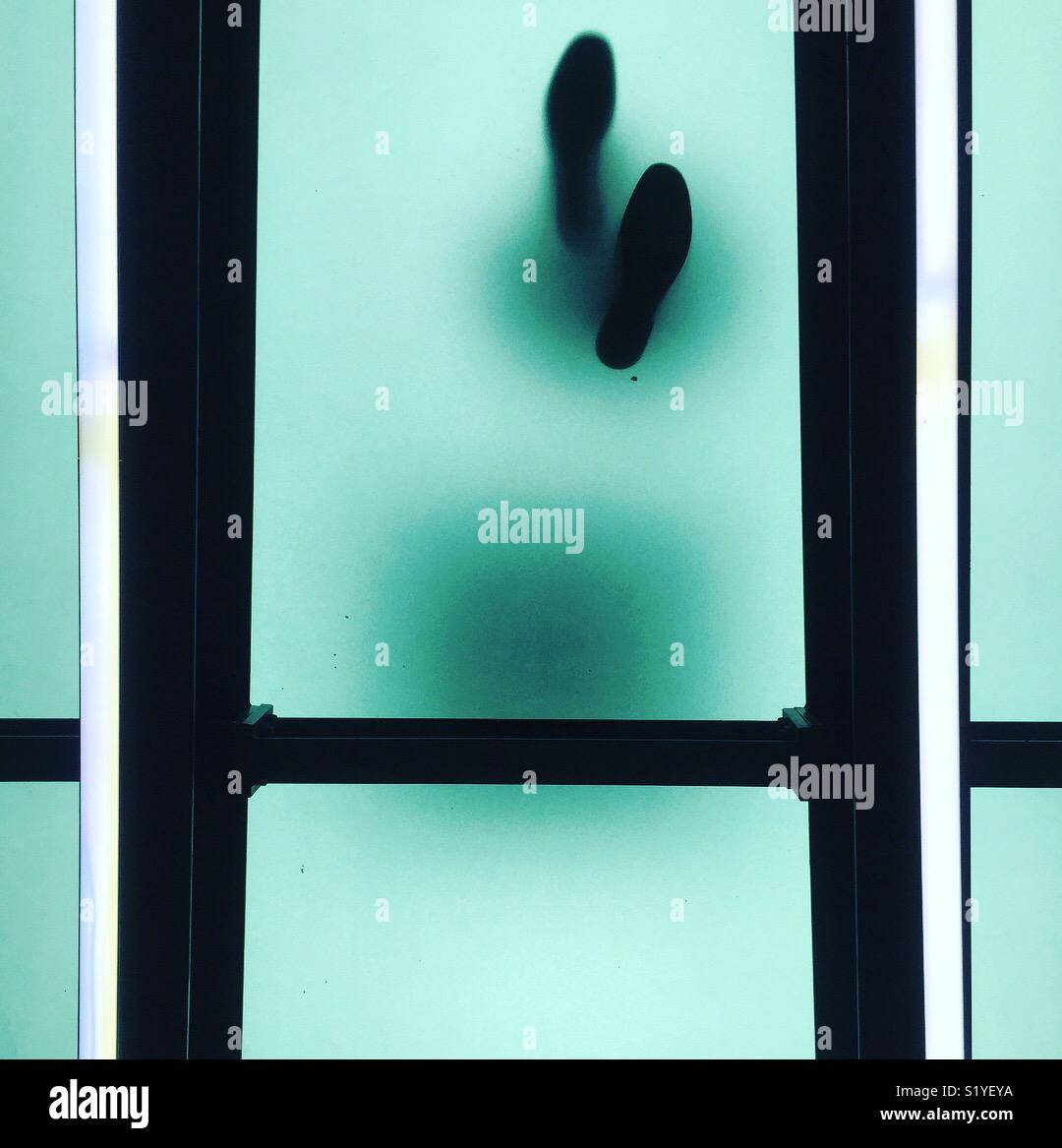 Pair of feet silhouetted through a glass floor Stock Photo - Alamy