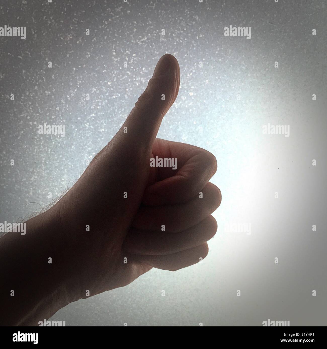 Giving the thumbs up against a frosty window on a sunny morning Stock ...