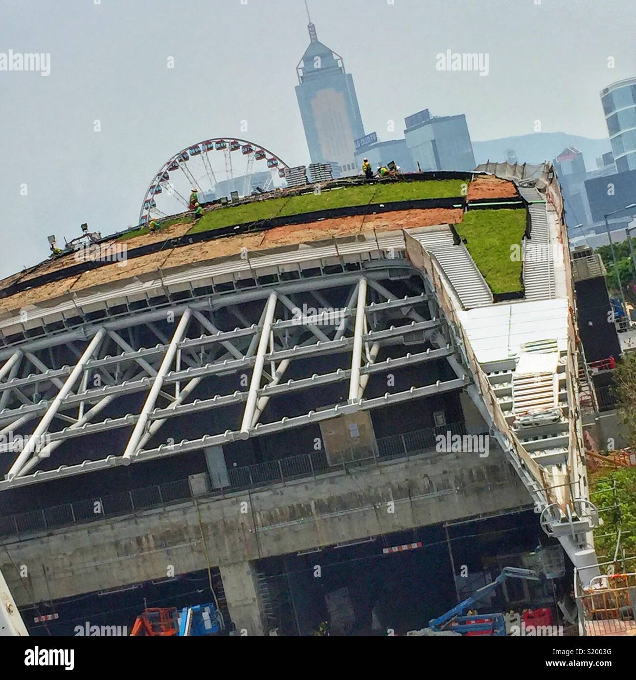 Workers lay grass turf for a ‘green roof’ on the building under ...