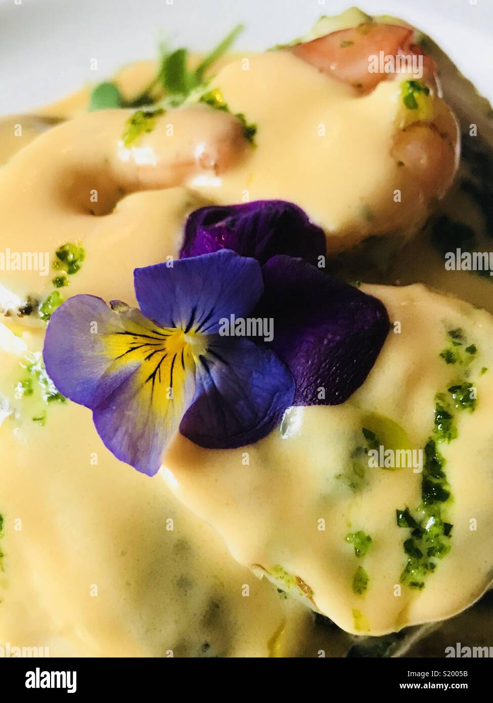 Baked halibut with a lobster sauce decorated with Viola flowers Stock ...