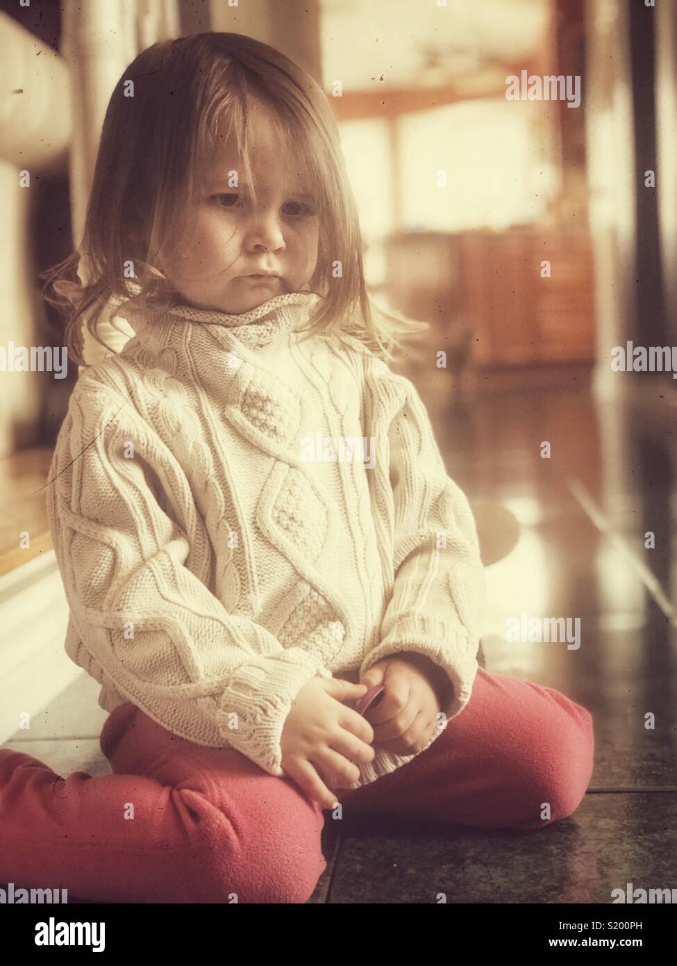 Warm airy image of sad, distraught preschool girl sitting on tile floor ...