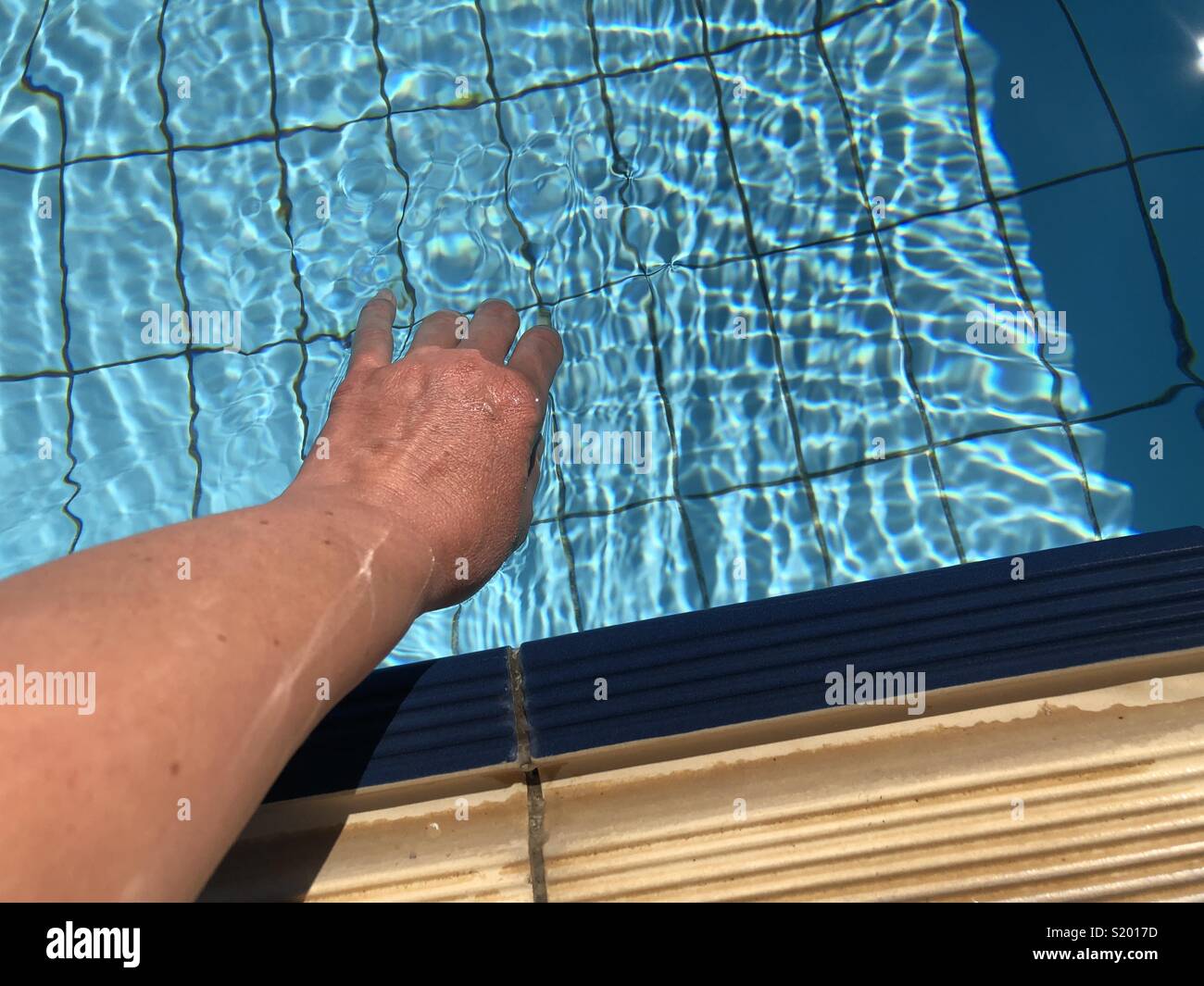 Hand and arm testing swimming pool’s water temperature Stock Photo - Alamy
