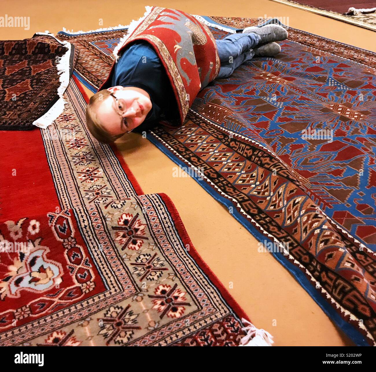 A boy goofing around rolls in a carpet Stock Photo - Alamy