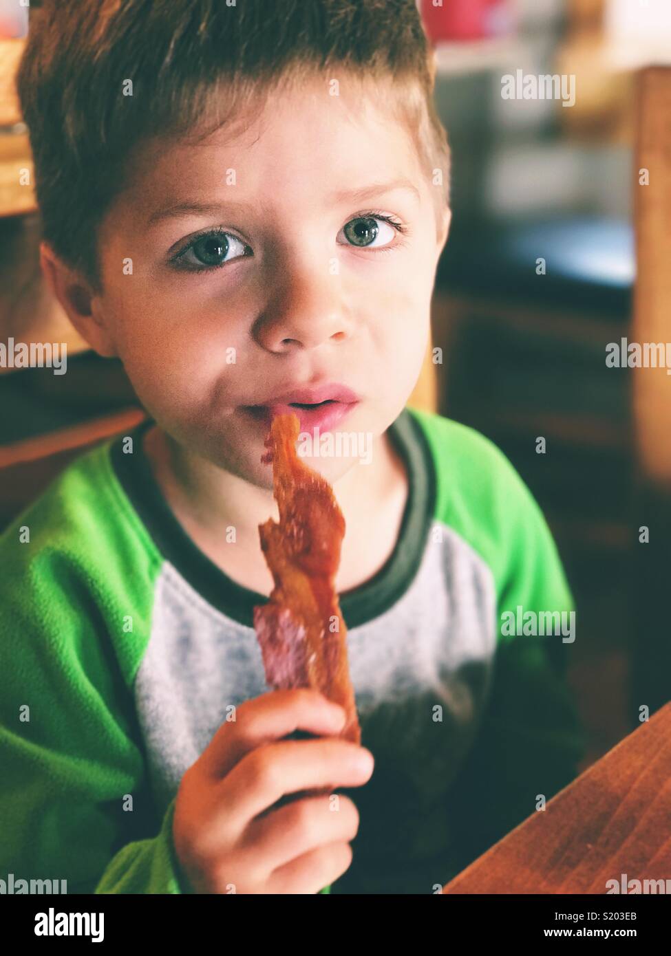 Boy eating bacon Stock Photo - Alamy