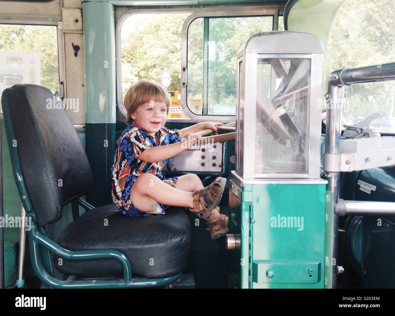 Happy boy behind drivers seat in vintage bus Stock Photo - Alamy