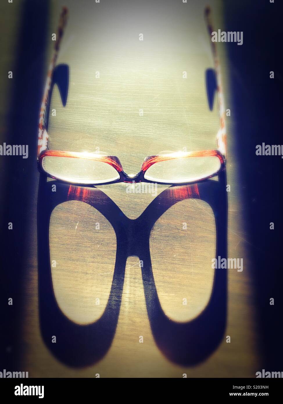 Eyeglasses on a table with shadow Stock Photo - Alamy