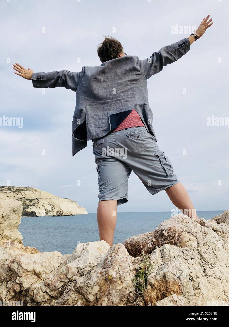 Man Celebrating success and life on a rock overlooking the sea Stock ...