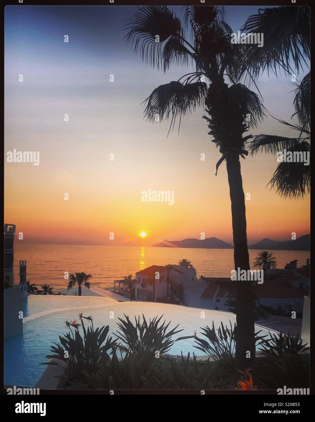 Sun setting over an infinity pool Stock Photo - Alamy