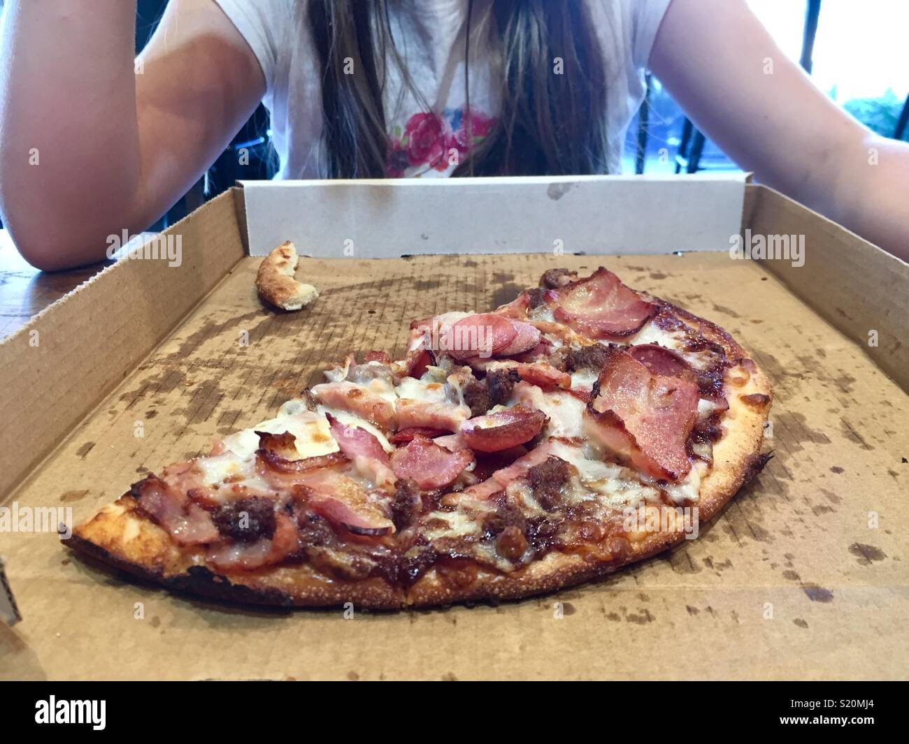 Half eaten takeaway pizza in front of a young girl Stock Photo - Alamy