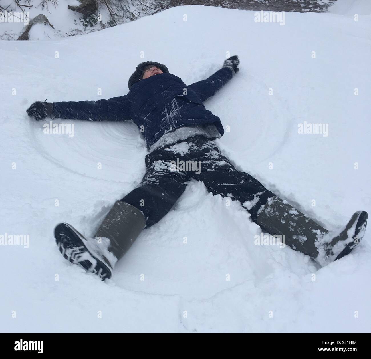 Boy being a snow angel Stock Photo - Alamy