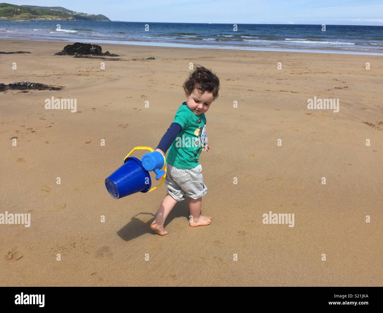Boy on beach with bucket Stock Photo - Alamy