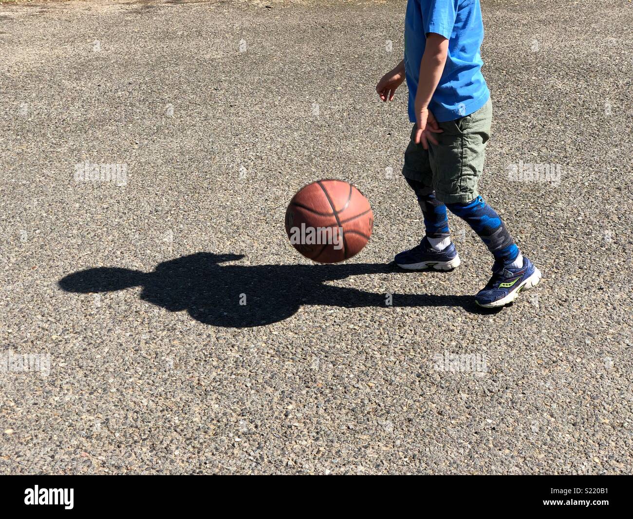 Boy playing basketball with shadow Stock Photo - Alamy