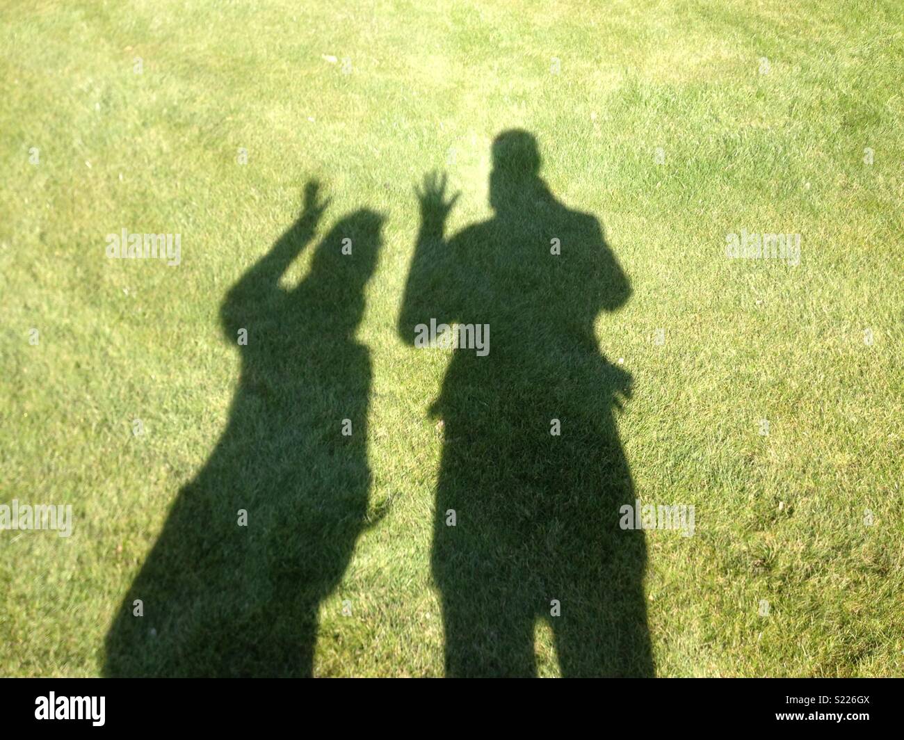 Shadows of two people on the grass Stock Photo - Alamy