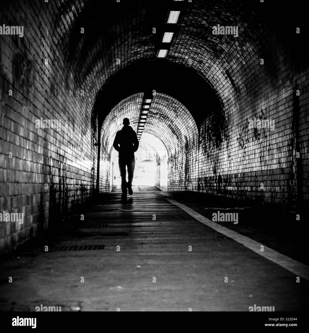 Man walking through a tunnel Stock Photo - Alamy