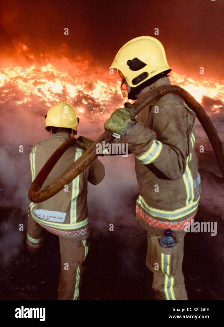 Two firefighters working together to extinguish a fire Stock Photo - Alamy