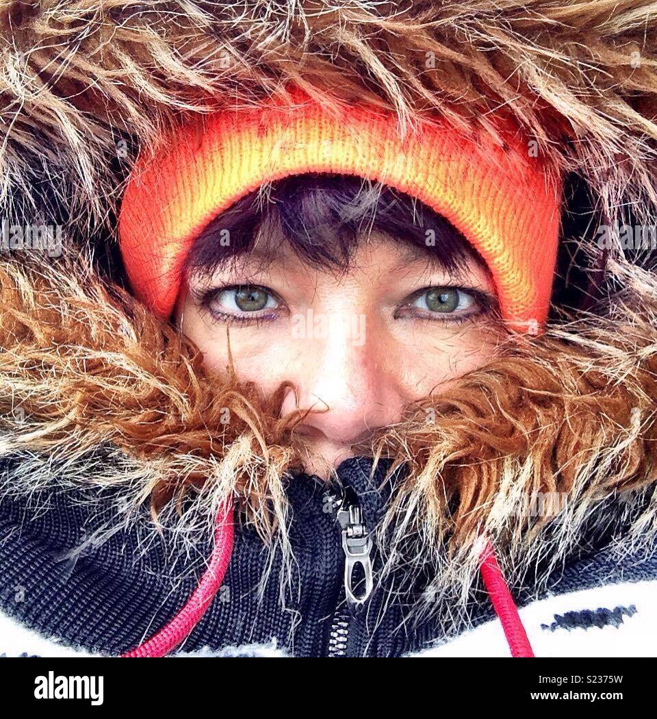 Woman with furry hood and orange hat. Eskimo features. Nose and eyes ...