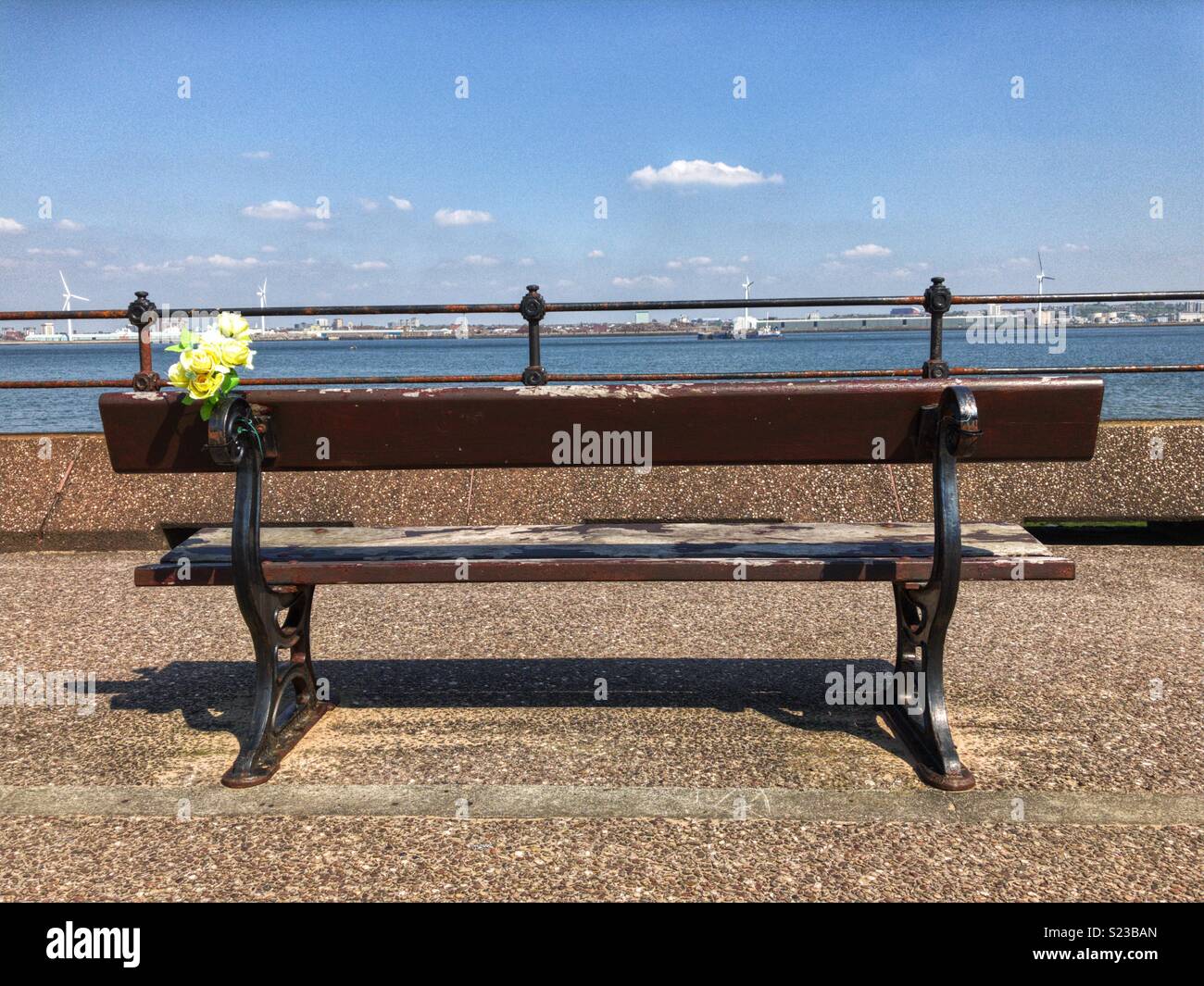 A bench, with flowers, on the promenade looking over the River Mersey ...