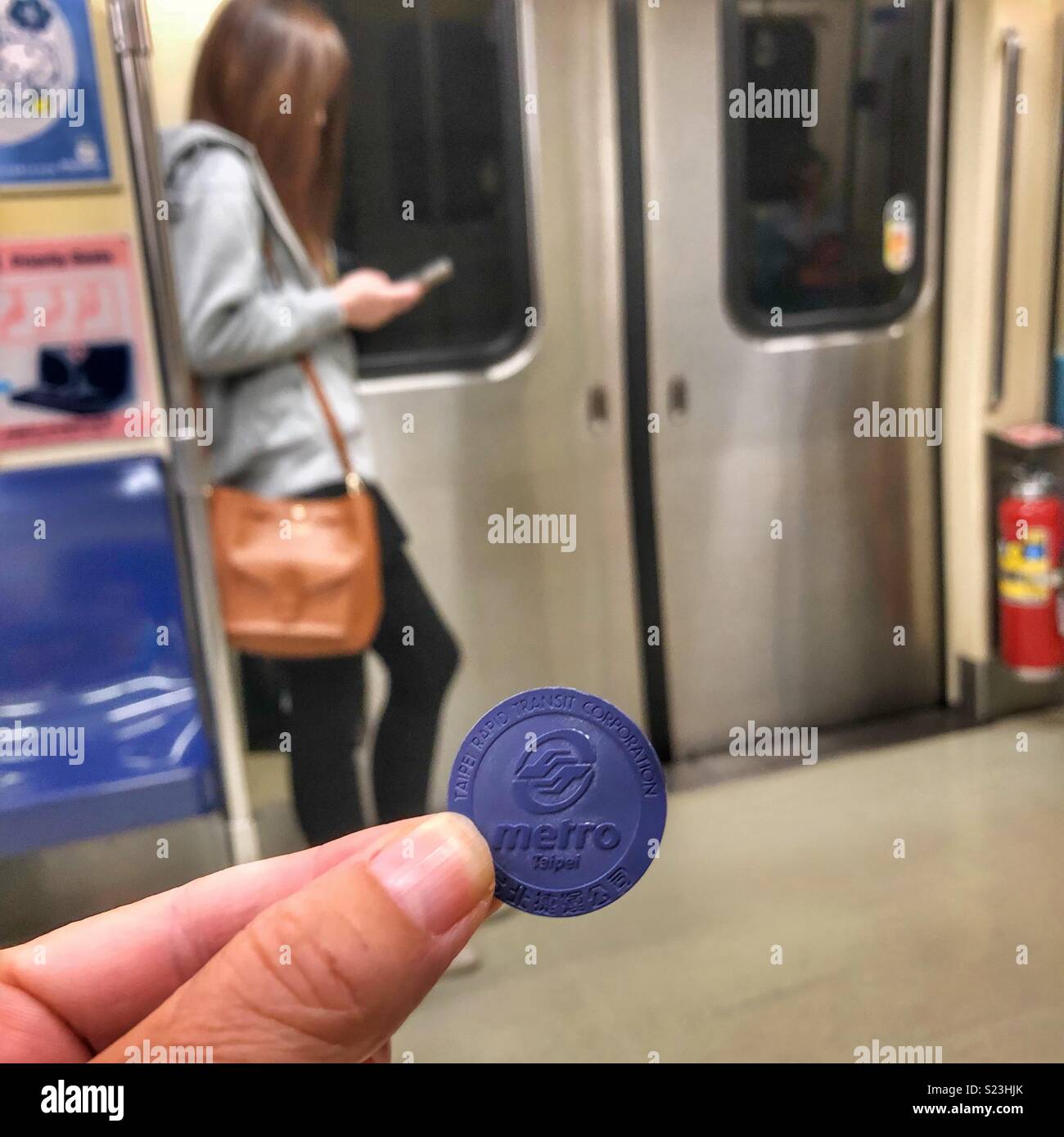 Fingers hold a Taipei metro token Stock Photo - Alamy