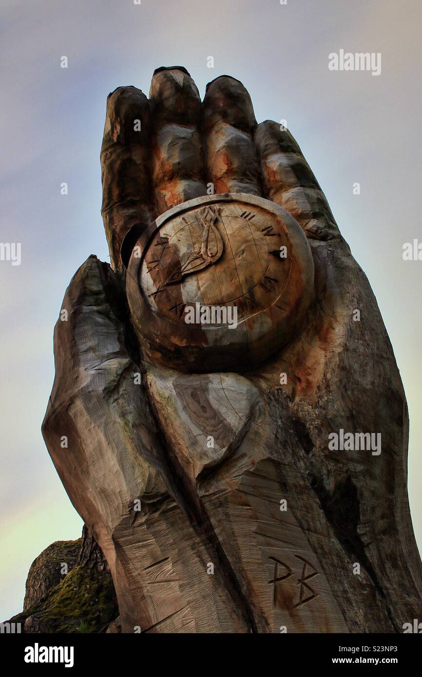 Carved tree trunk into shape of hand with clock Stock Photo - Alamy