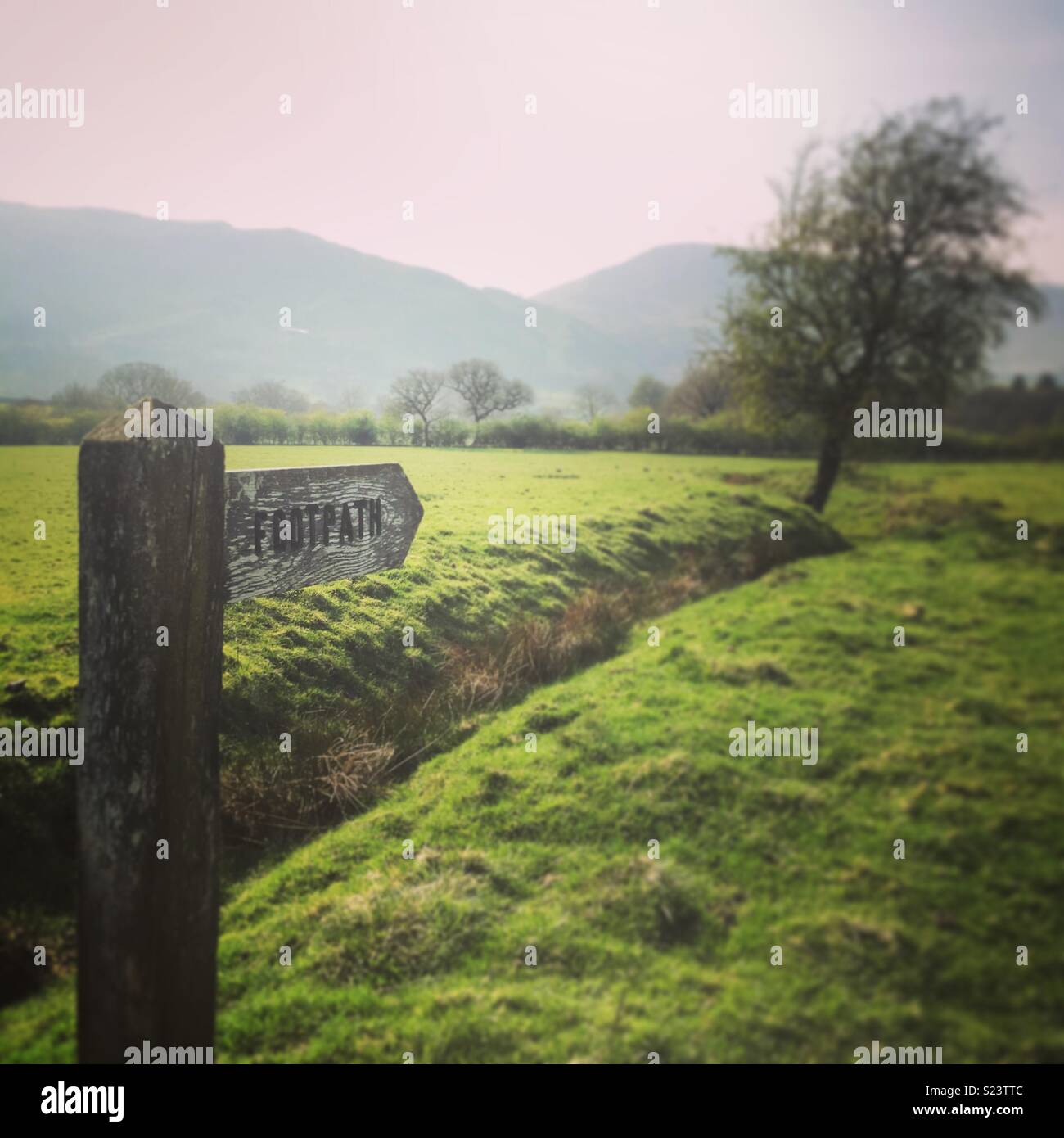 Footpath sign pointing into the Peak District. Looking out over lush ...