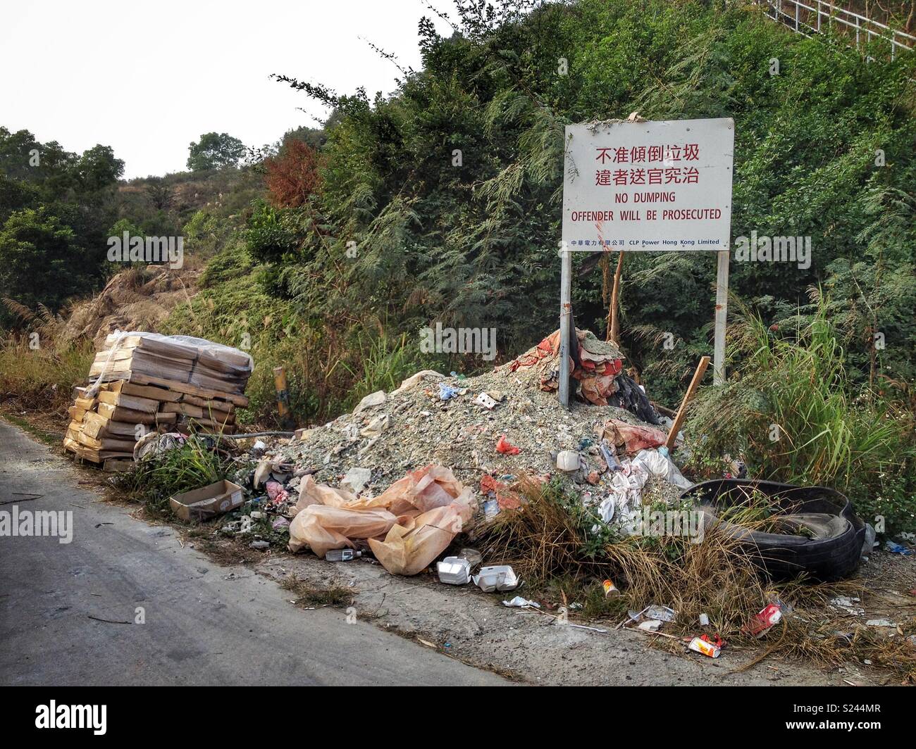 Bilingual 'No Dumping' sign in Chinese and English with illegally ...