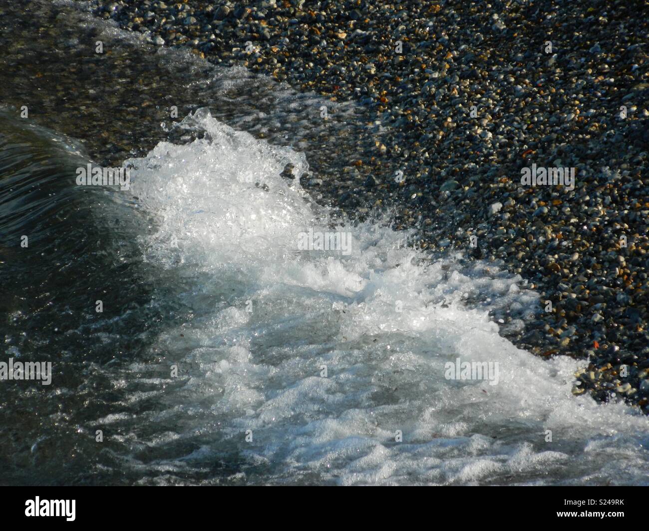 Water breaking on a beach Stock Photo - Alamy
