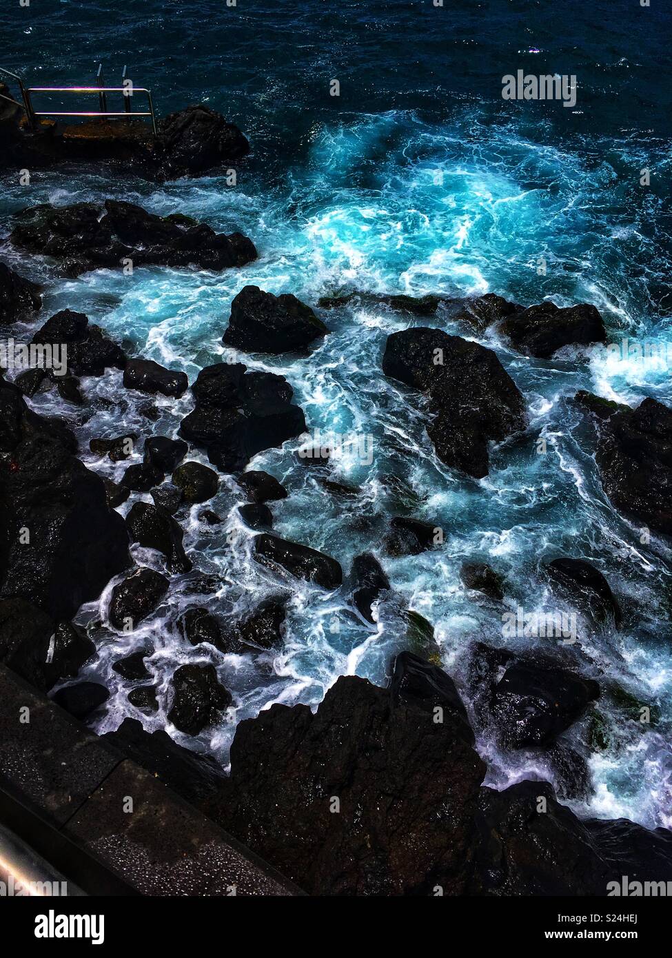 Swirly Sea and Black Rock Stock Photo - Alamy