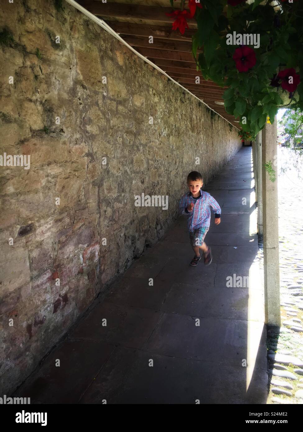 Boy running down a covered walkway Stock Photo - Alamy