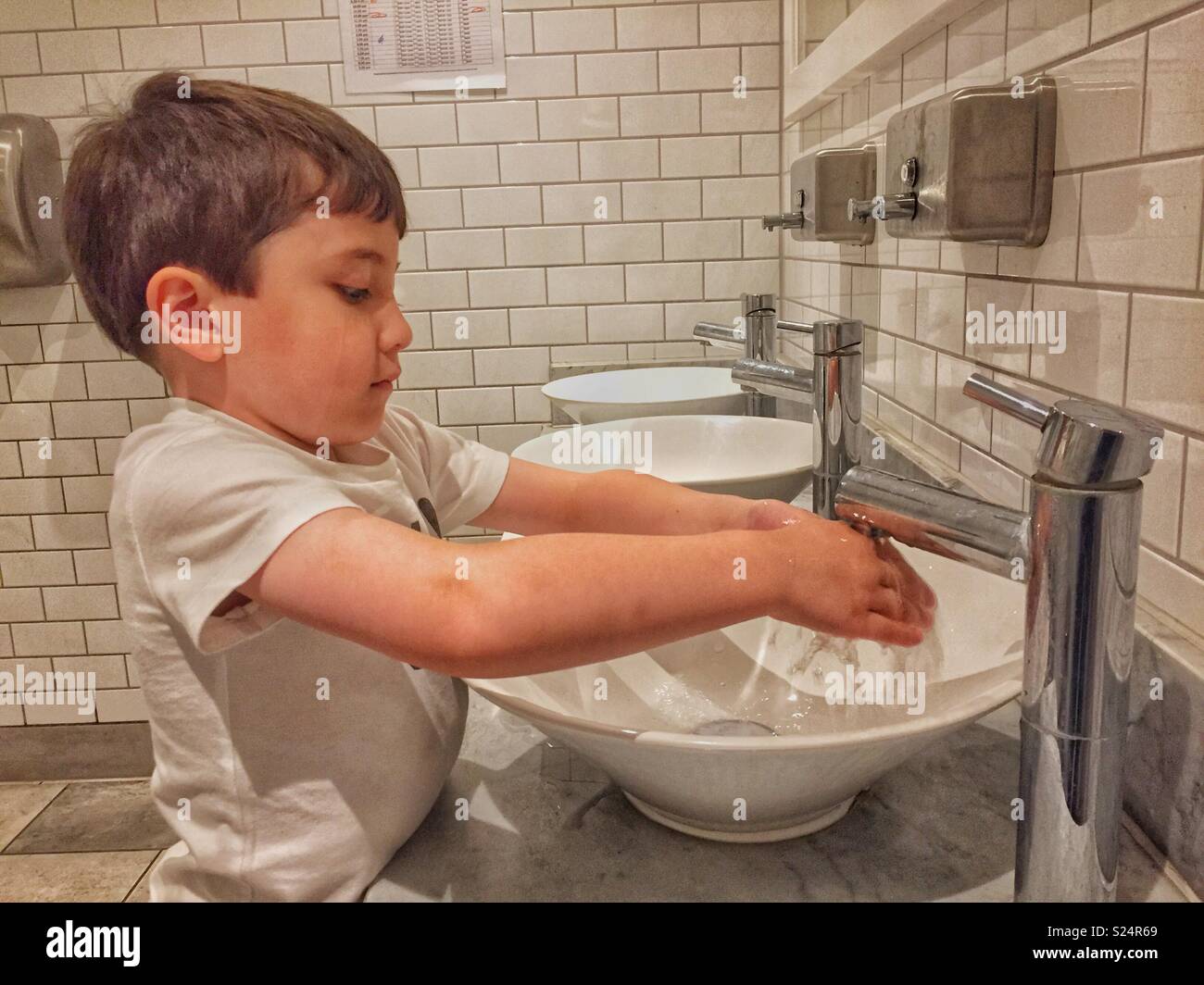 A young boy washes his hands at a sink in a public toilet Stock Photo ...