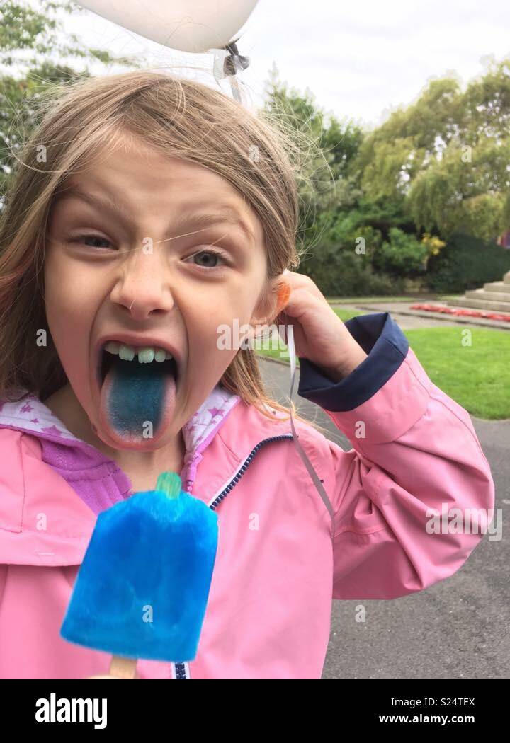 Girl enjoying blue ice lolly Stock Photo - Alamy