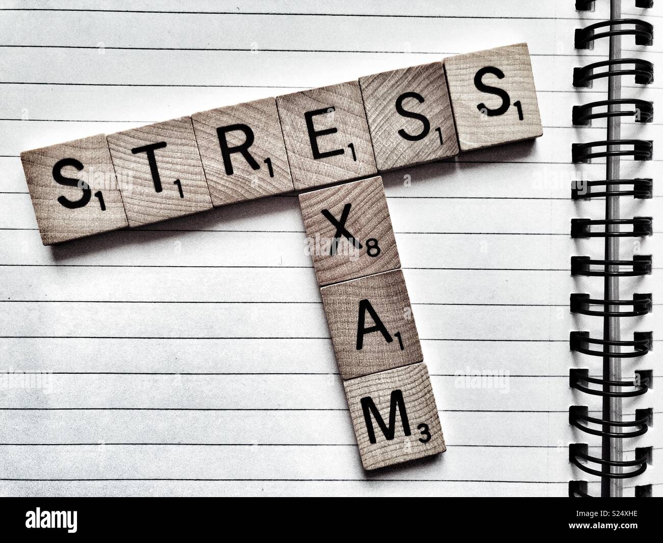 Exam Stress in wooden letters on an open, empty, spiral bound notebook ...