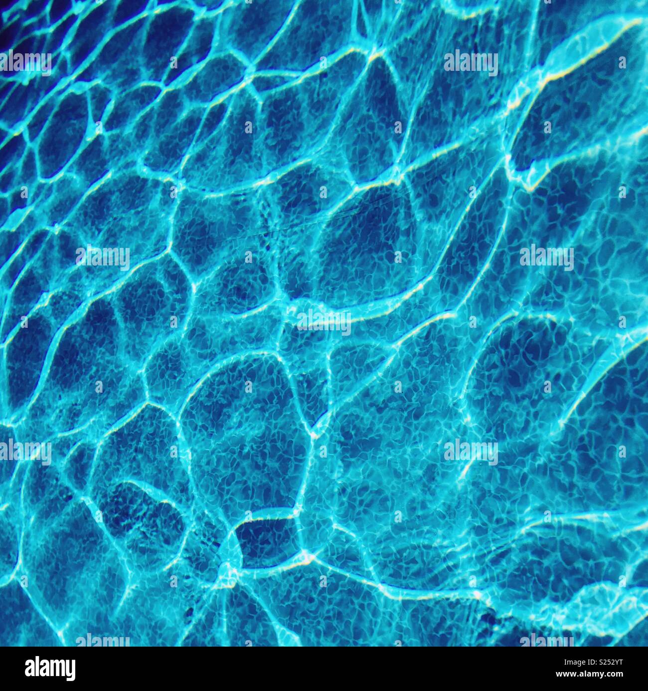 Underwater light reflections in an outdoor swimming pool. Square crop ...